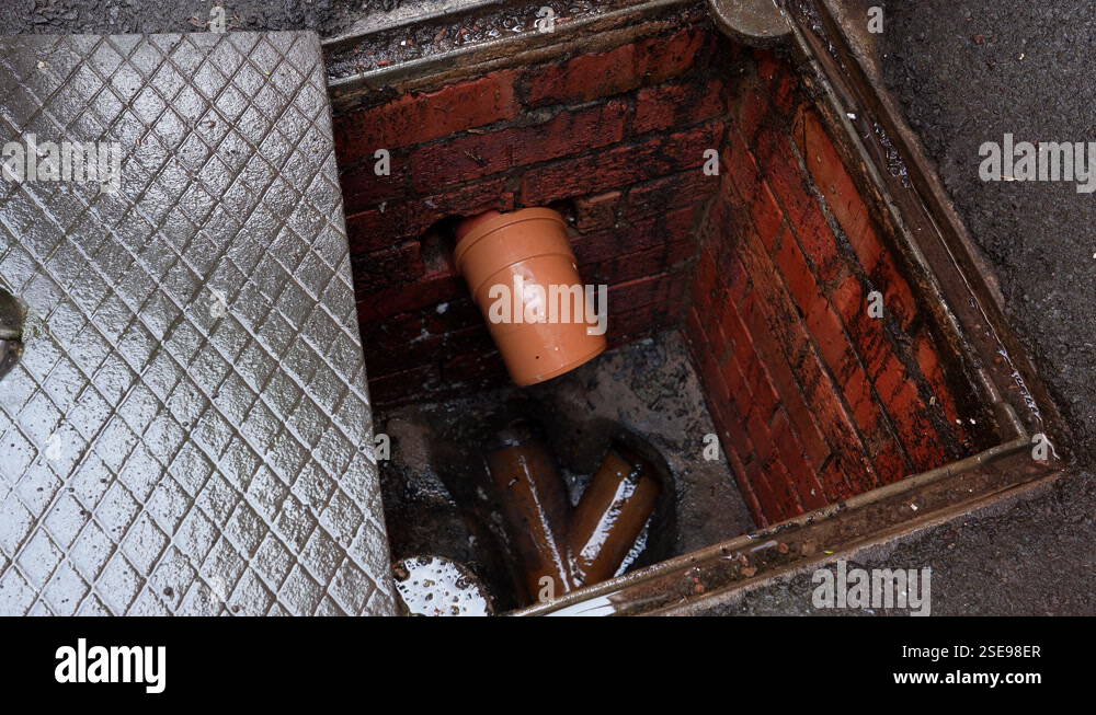 Removing manhole cover and inspecting drain male worker with green ...