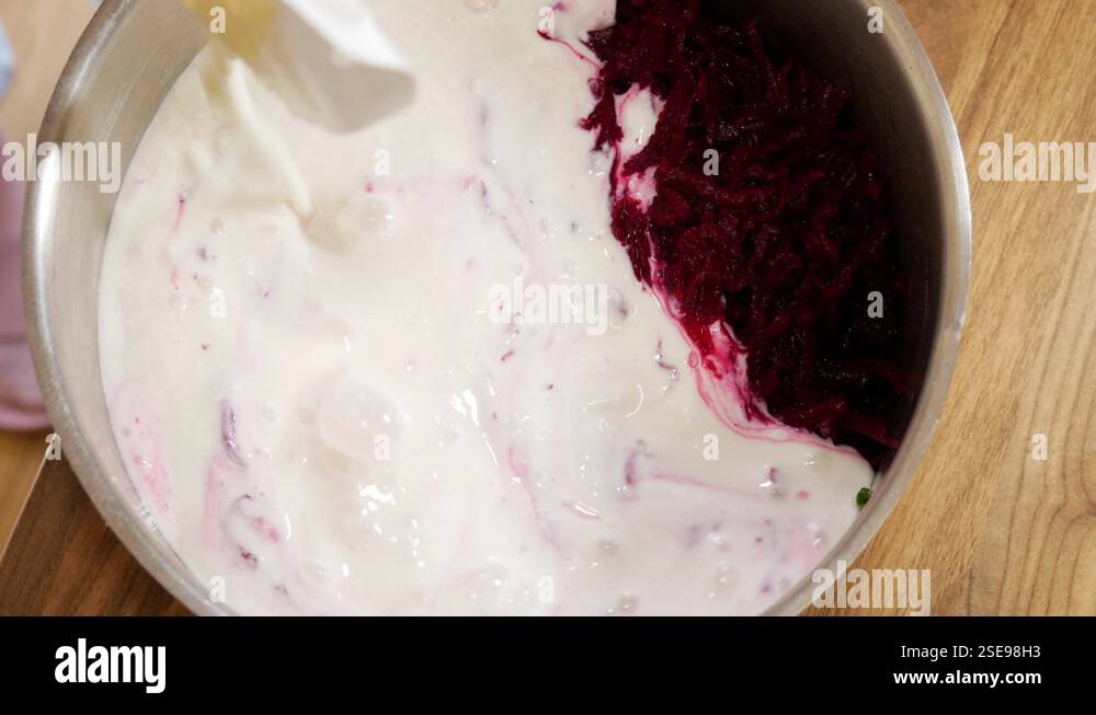 Pouring kefir into bowl with ingredients for cold beetroot soup, static ...