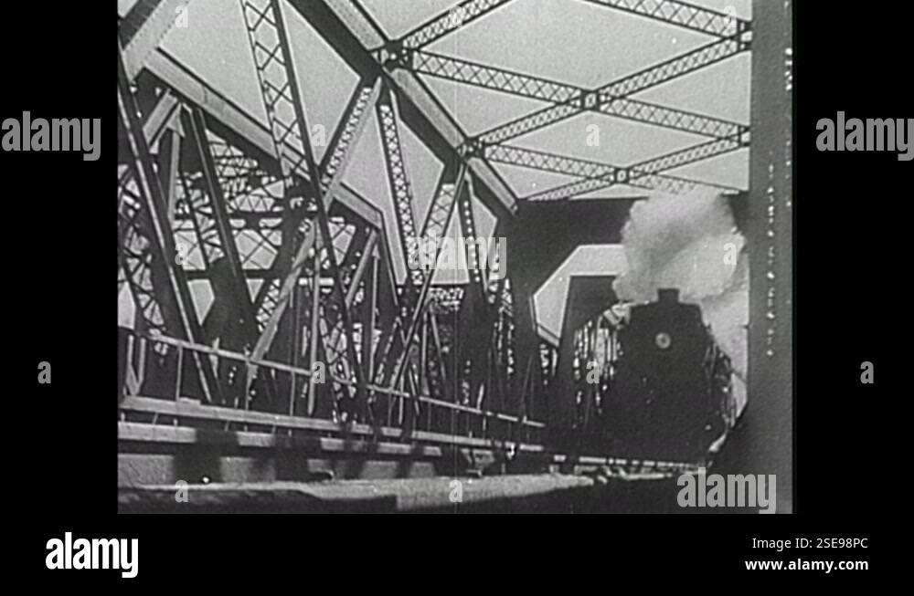 1940s: Train crosses bridge over gorge. Train carries trucks. Hair ...