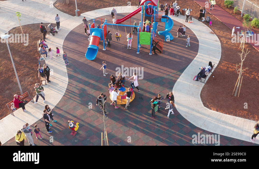 Playground for kids in a park, busy with children having fun and ...