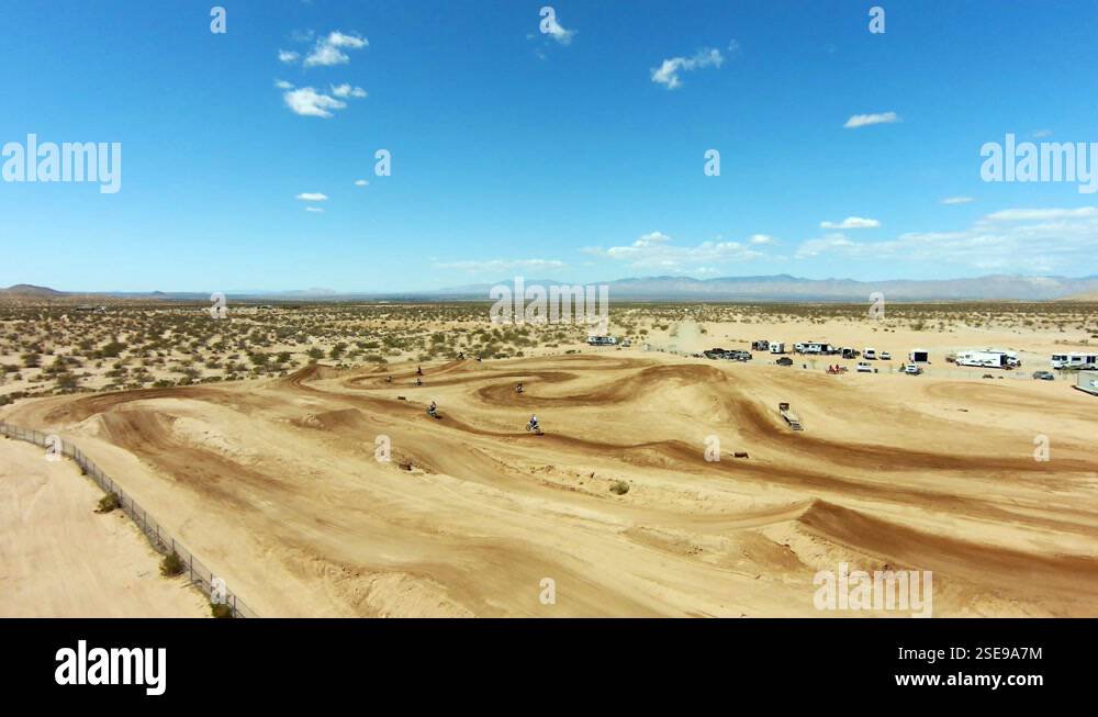 Motorcycles making long jumps at a desert off-road race track - aerial ...