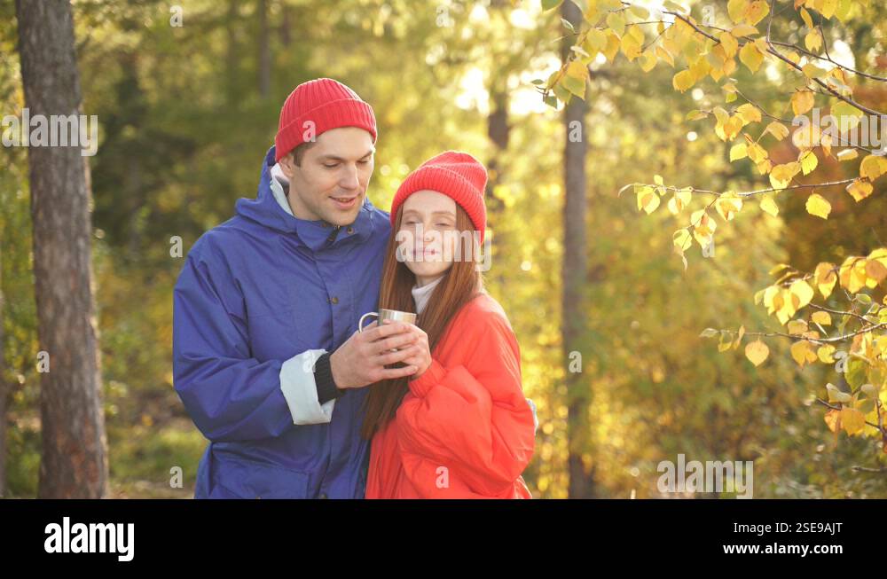 Attractive couple tourists stands in autumn forest with cup of tea and ...