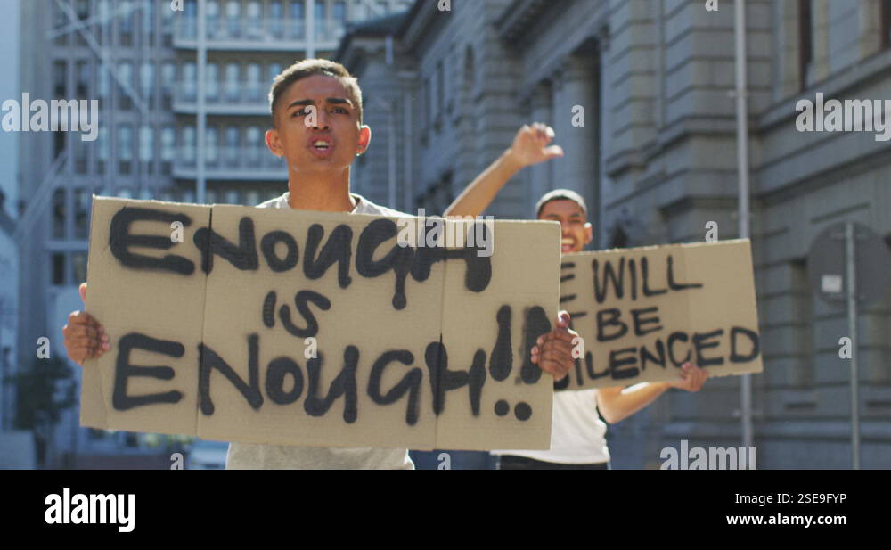 Two mixed race men on a protest march holding placards raising hands ...