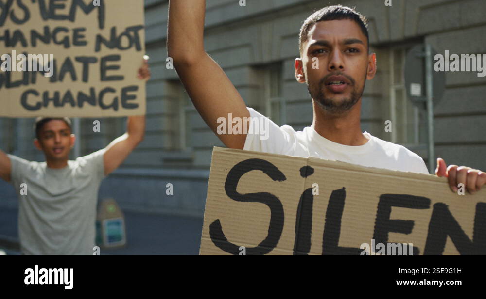 Two mixed race men on a protest march holding placards raising hands ...
