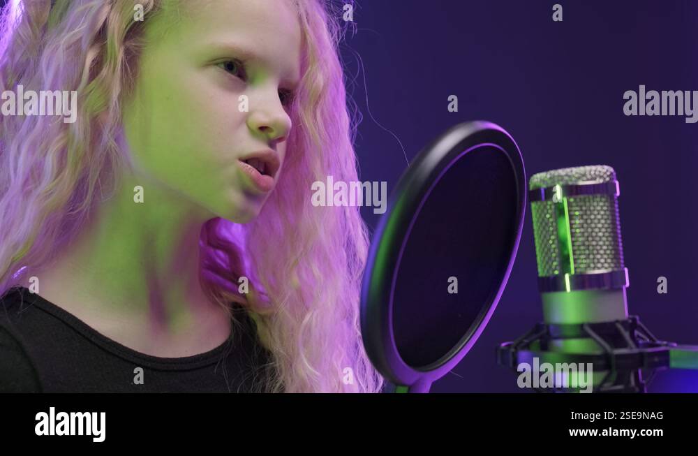 Young blonde girl singer sings into microphone in professional recording studio Stock Video ...
