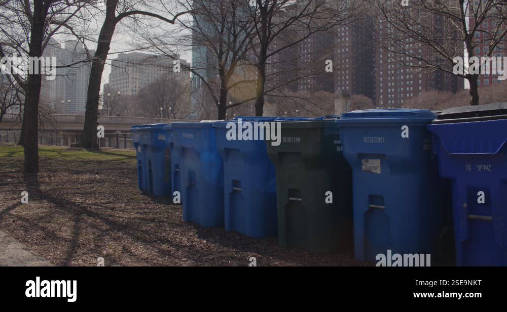 Panning camera footage of lined up recycling and garbage cans in an ...