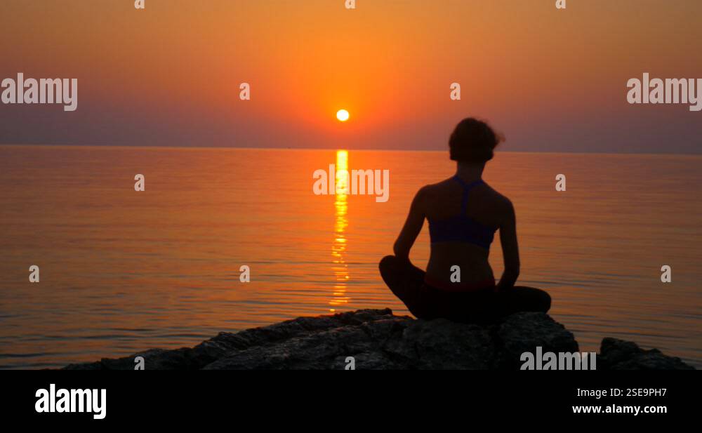 Girl practices yoga near the ocean during sunrise time, lotus pose, sun ...