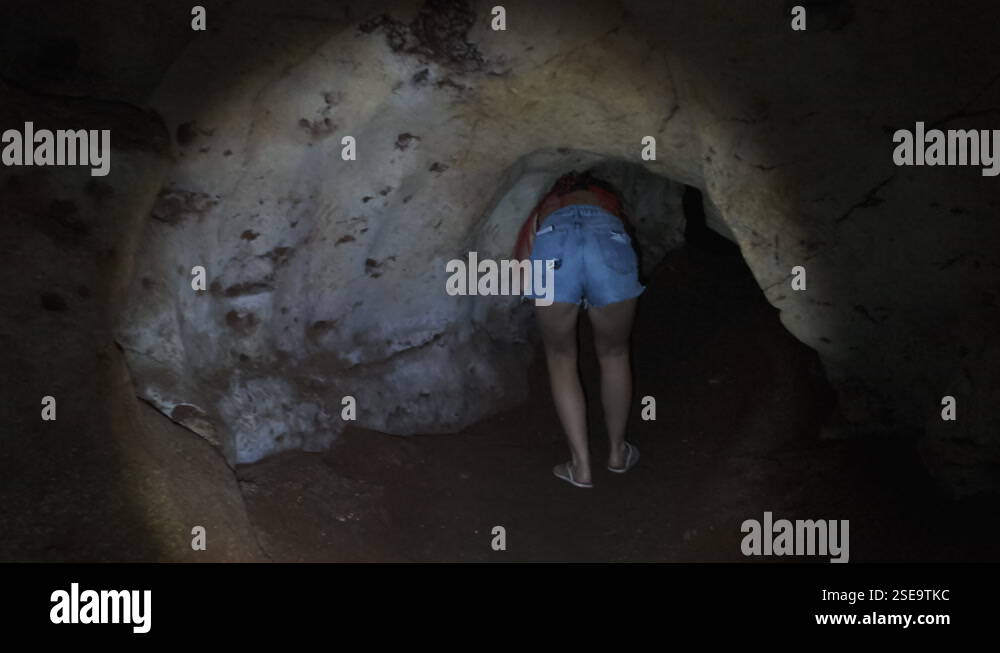Woman Explores Stalactites Inside a Deep Dark Cave, Illuminating with ...