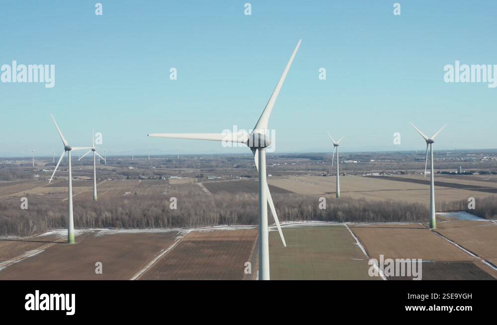 drone flying in a wind farm approaching a wind turbine front the back ...