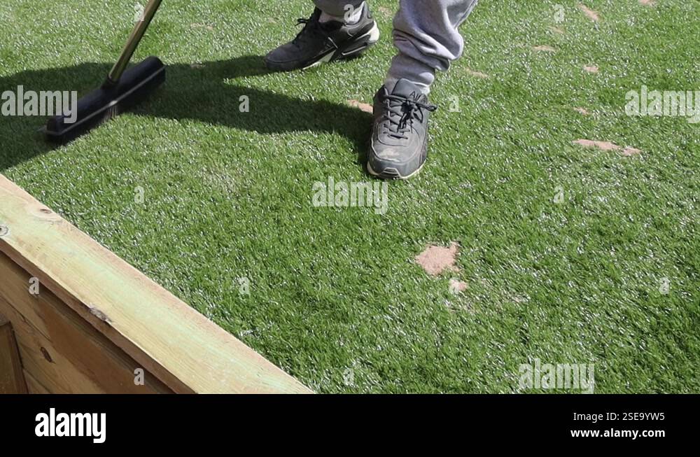 Close up of man sweeping sand into artificial grass Stock Video Footage ...