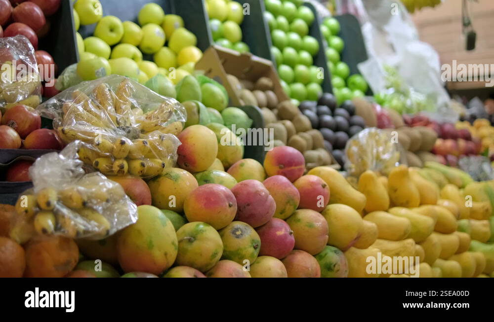 Colorful fruit stand with tangerines, apples, mangoes, bananas, and ...