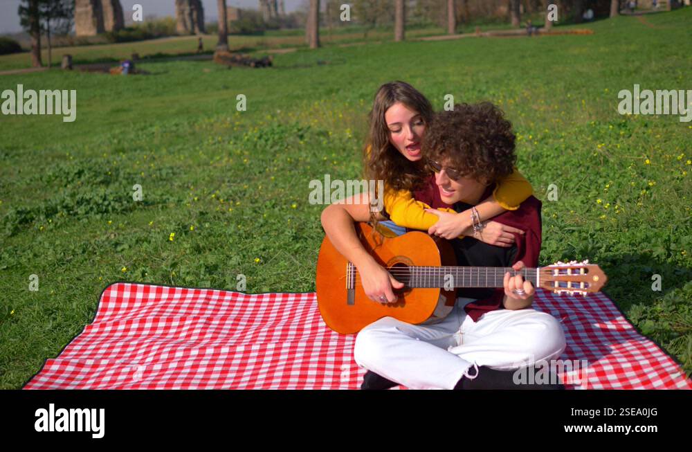 girl sings at the park hugging her boyfriend who plays the guitar Stock ...