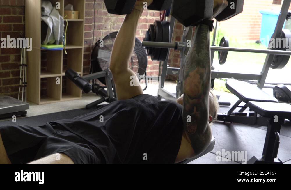 Muscly man in home gym exercising close grip dumbbell tricep press on ...