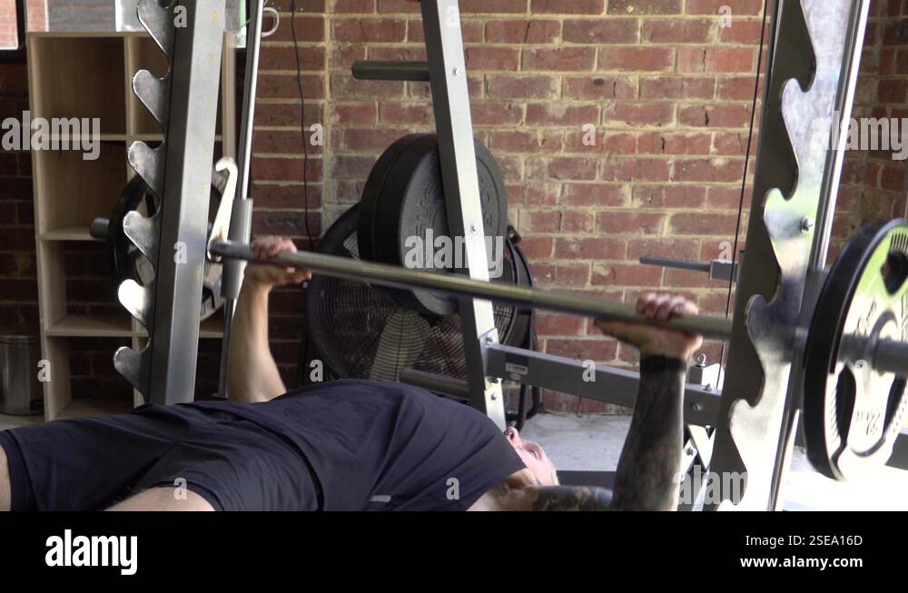 Muscly man in home gym exercising decline smith machine bench press ...