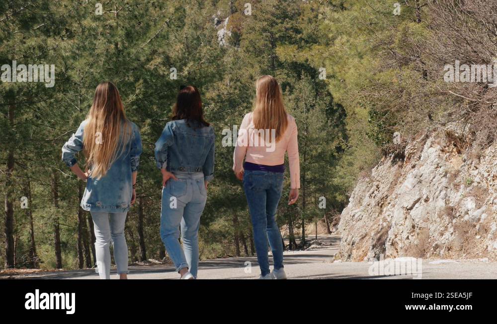 Tree young woman in jeans wear walking confidently in the pine trees ...