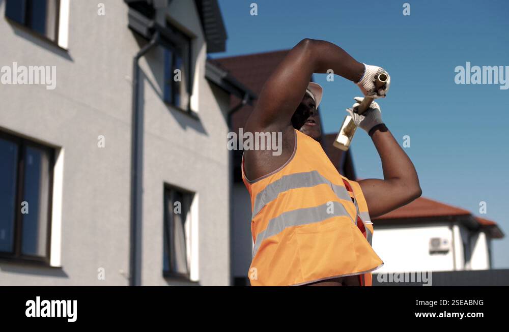 Muscular African American in uniform waving a sledgehammer at a ...