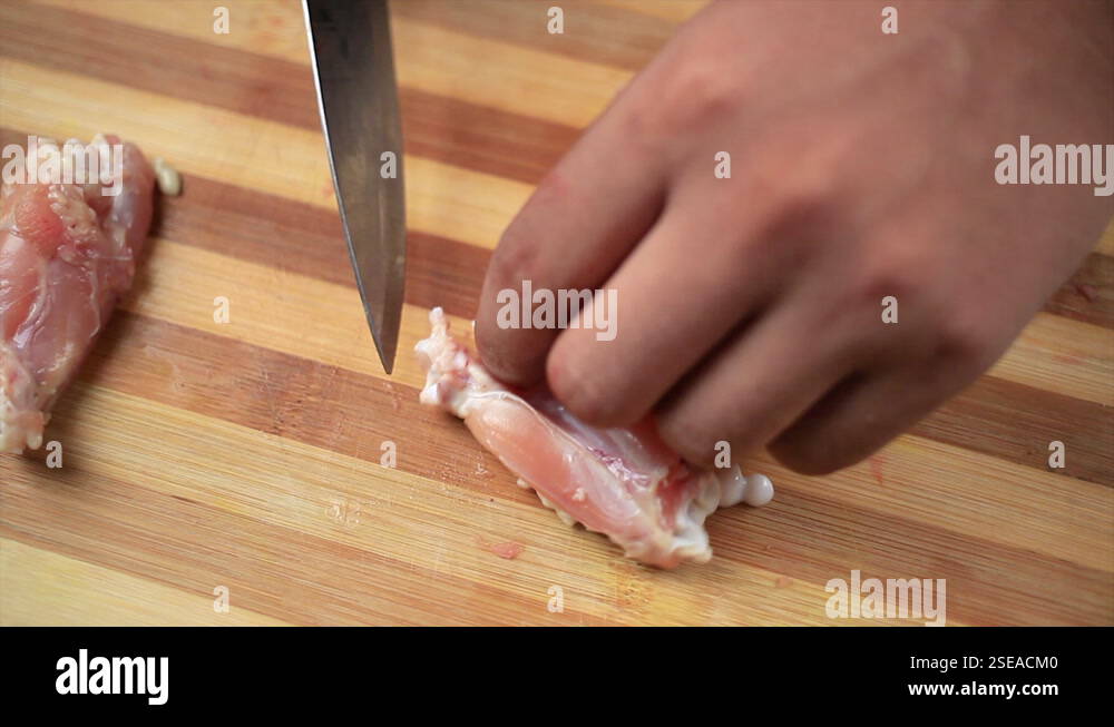 fresh chicken wings cut by a butcher with a knife to bring a shape of ...