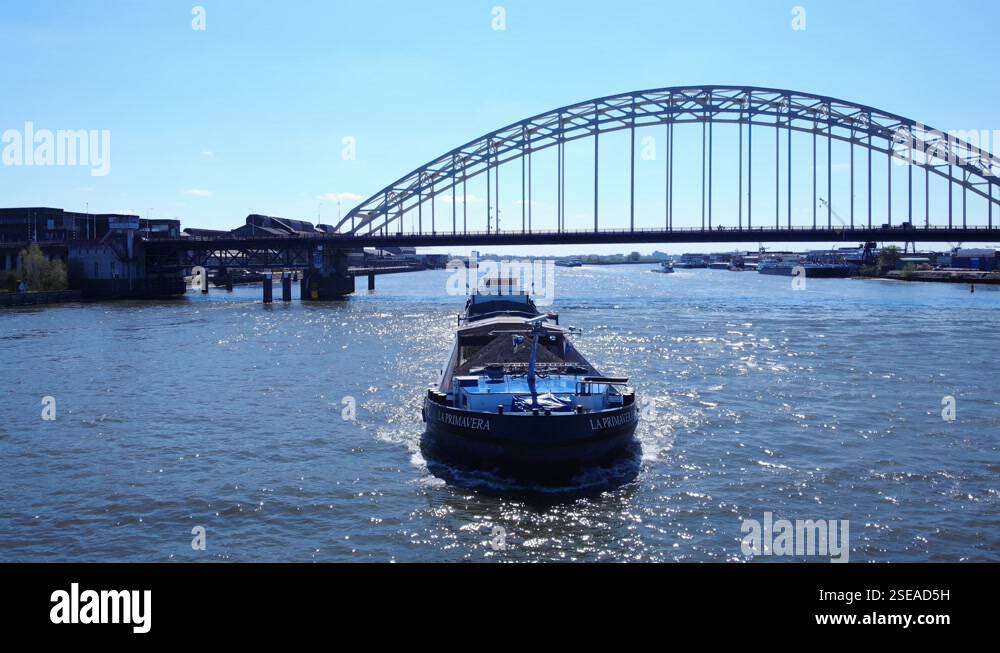 Merchant Vessel Crossing At River Noord With Arch Bridge Behind Near ...