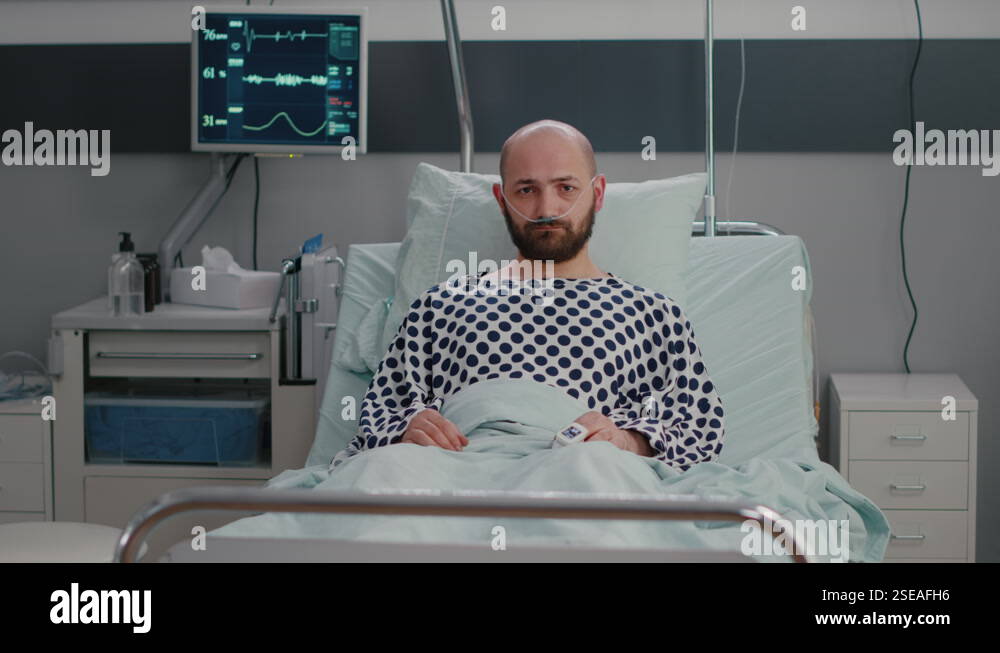 Potrait of sad sick man wearing nasal oxygen tube lying in bad looking ...