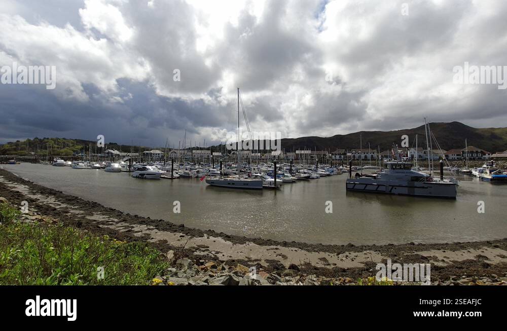 Floating marine vessels on Welsh Conwy marina under stormy overcast ...