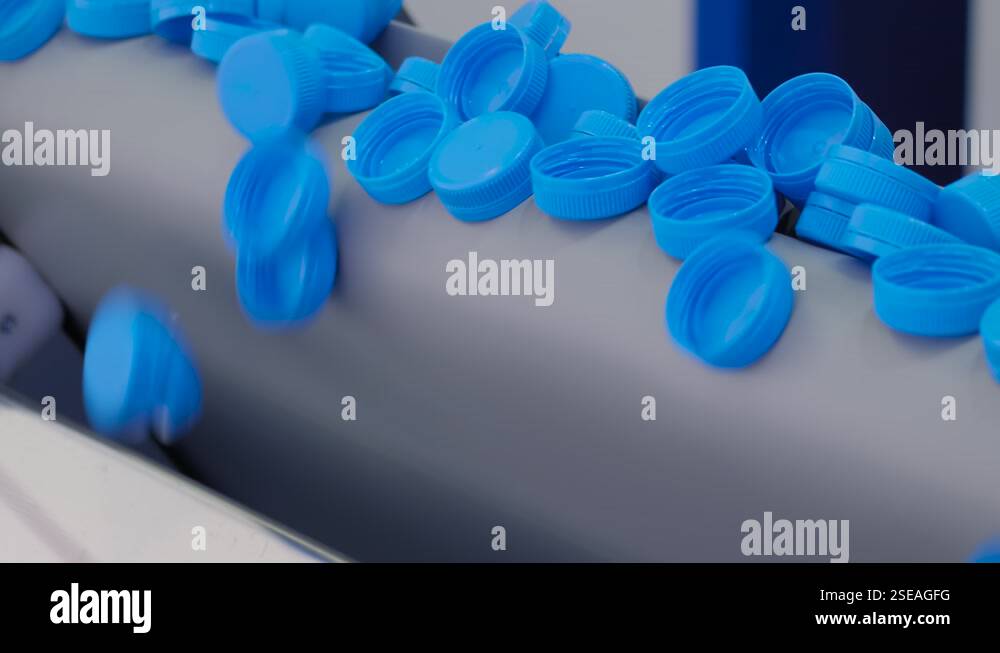 Many blue plastic bottle caps falling from conveyor belt - close up ...