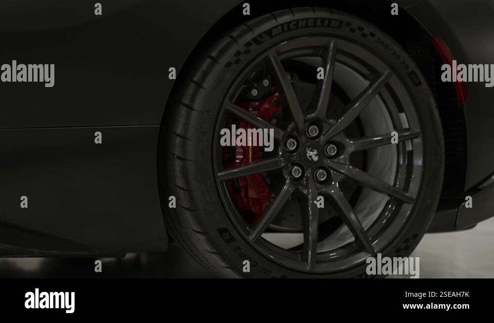A tire and rim of a black ferrari with red caliber breaks, zoom out ...