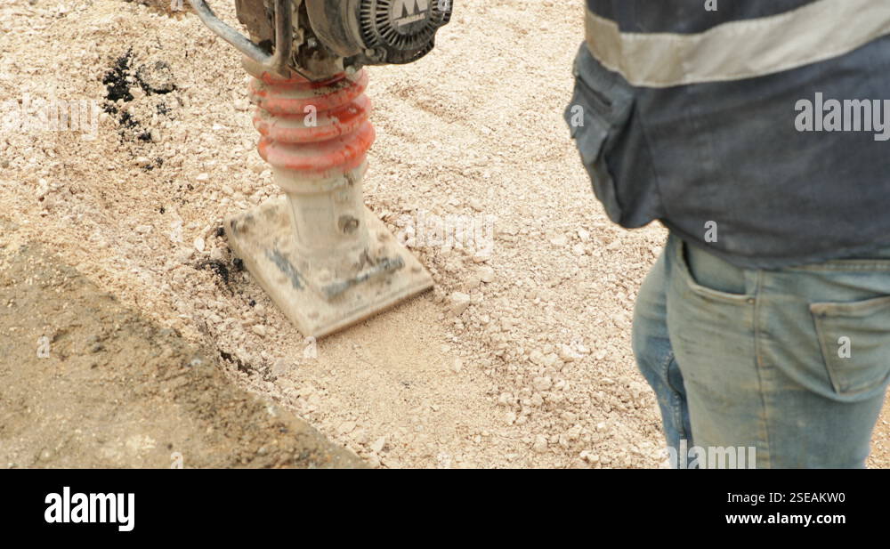 Worker With Vibrating Machine Is Compacting Soil At The Construction ...