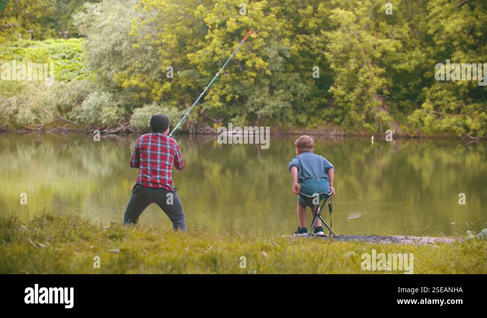 Two brothers on fishing - man pulling the rod and his little brother ...