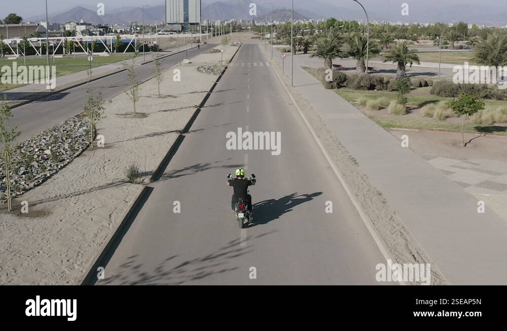 Aerial shot of chopper style motorcycle passing through empty street ...