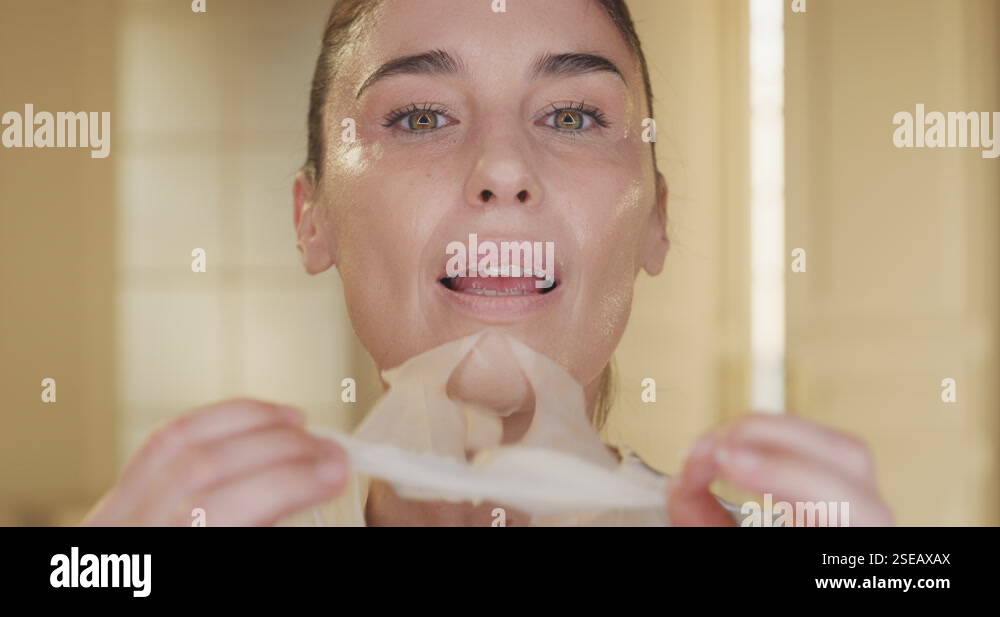 Mature woman taking off paper sheet mask from her clean face touching ...