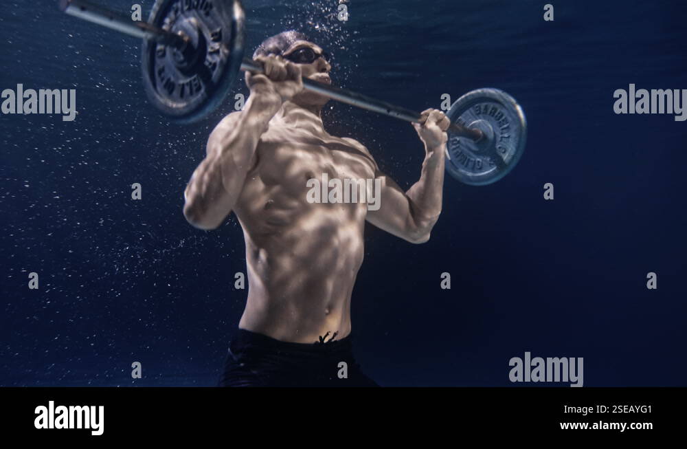 Male bodybuilder lifting barbell with determination barbell underwater ...