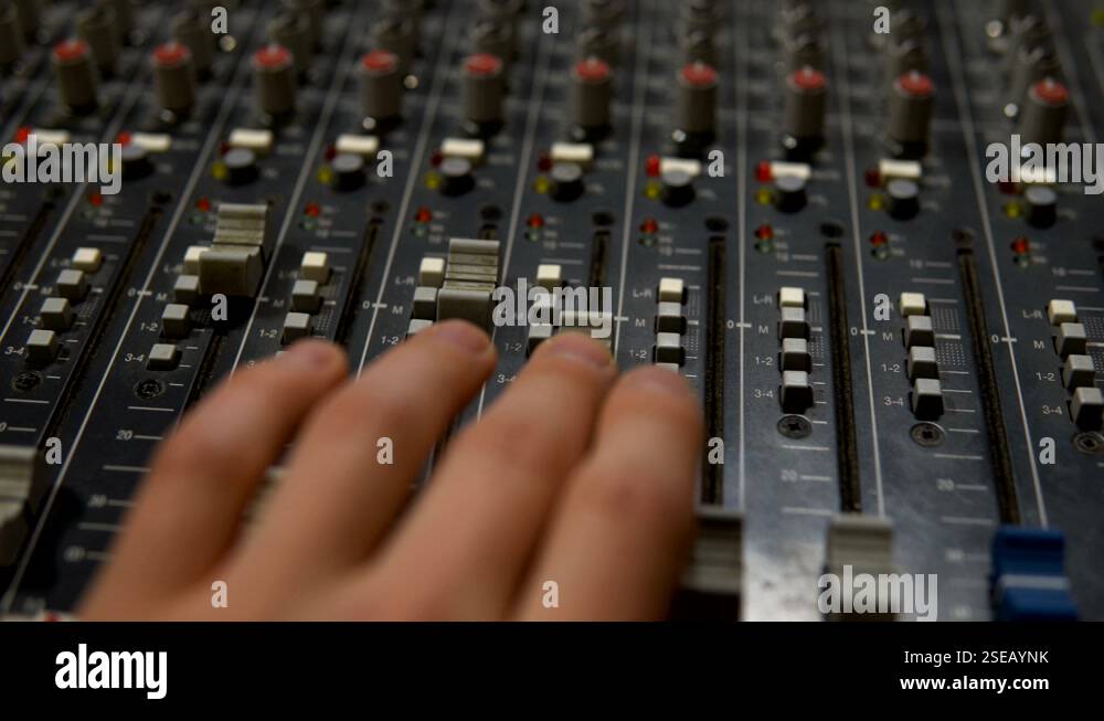 The man adjusts the sound using the sliders on the panel. Mixer for ...