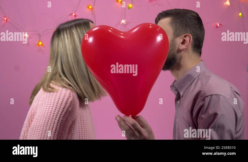 Couple in love man and woman kiss each other, hiding behind a balloon ...