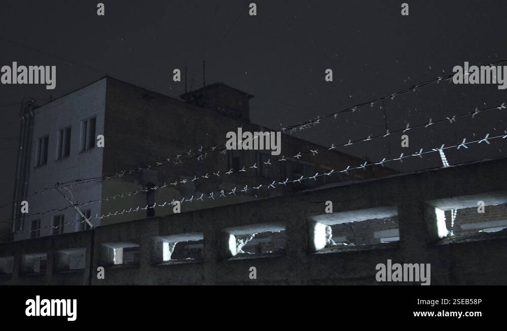 prison barbed wire over concrete fence at cold dark winter night during ...