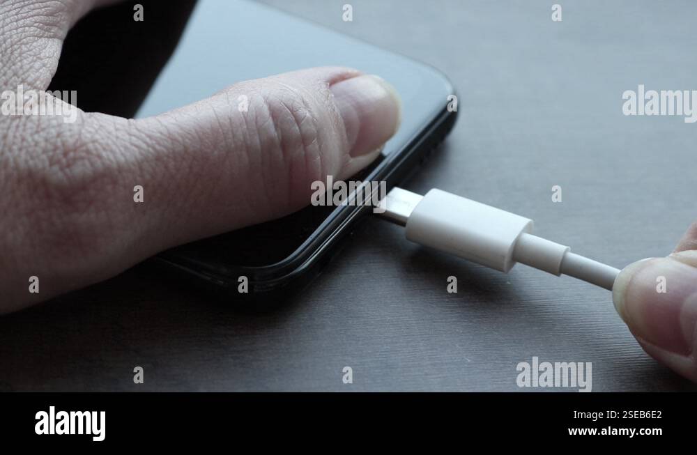 Woman plugging a USB type C cable into a smartphone connector to charge ...