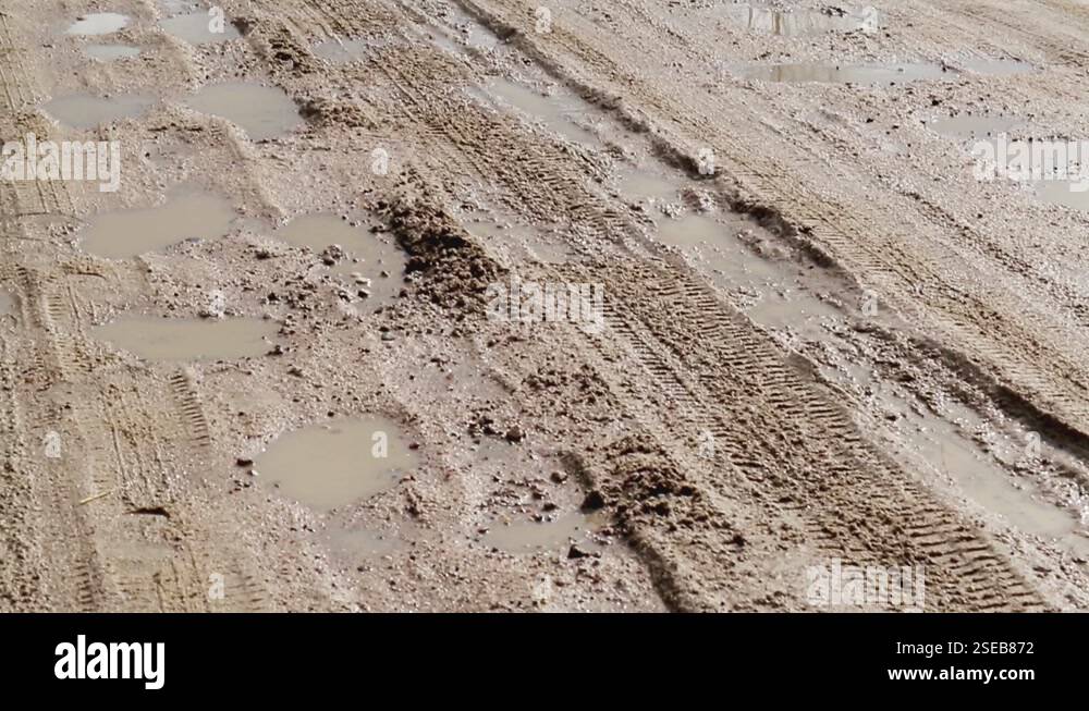 Bad gravel road with pits and puddles, in the background. Rocks and ...