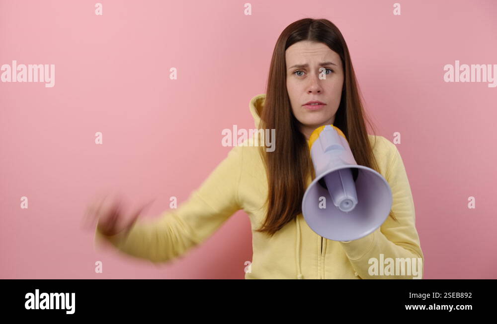 Displeased girl looking away screaming in megaphone showing thumb down ...