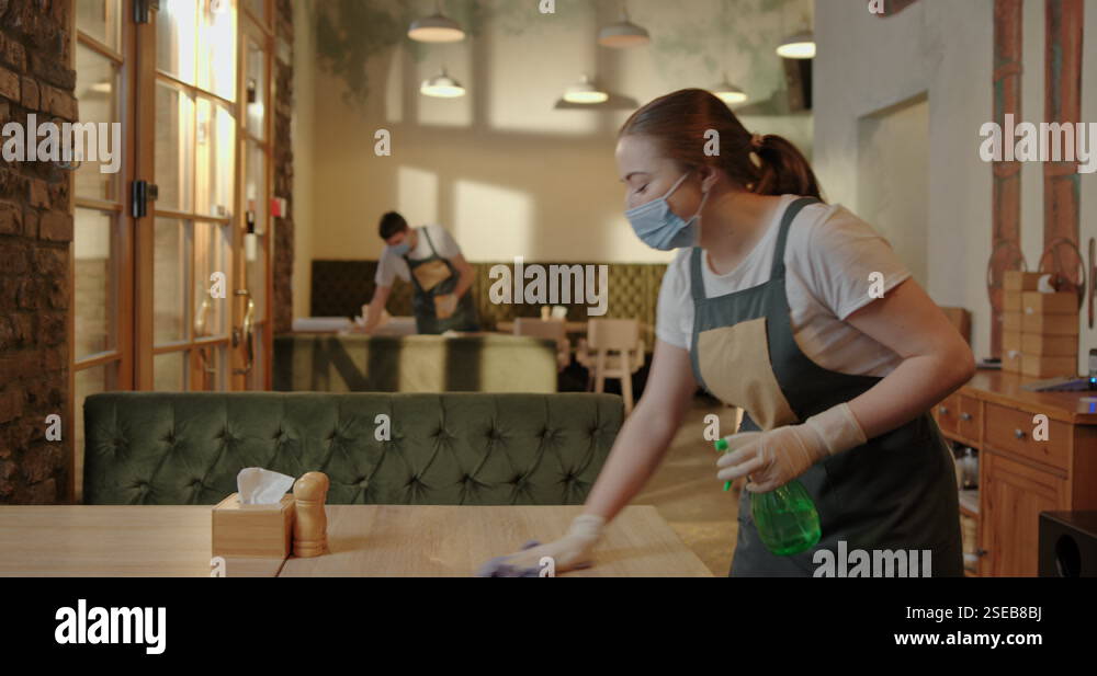 Cleaning disinfection of tables in a cafe two waiter workers a girl and ...