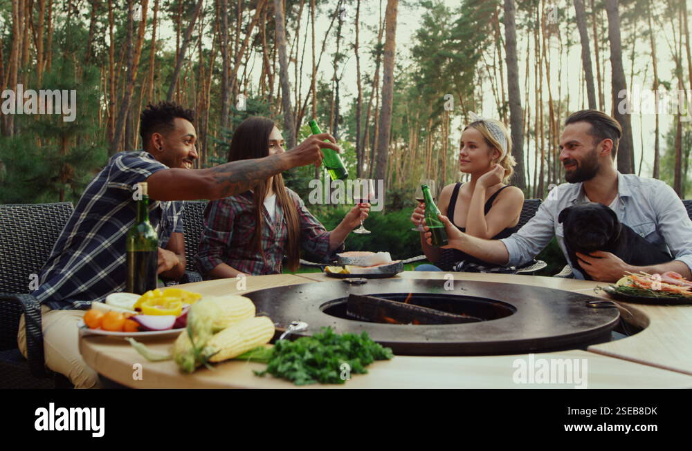 Happy friends celebrating near bbq grill outdoors. People talking on ...