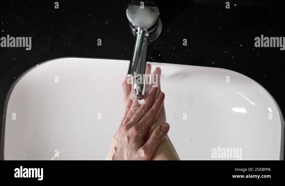 person is washing hands in bathroom, top view on hands under stream of ...