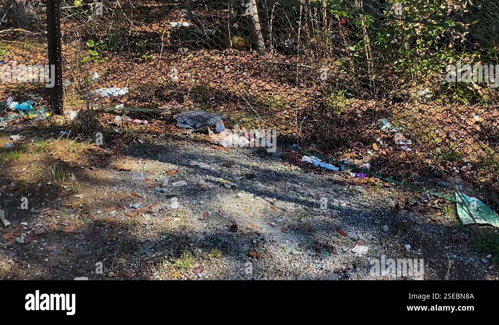 Tilt up of Trash build up behind a green chain link fence in rural ...