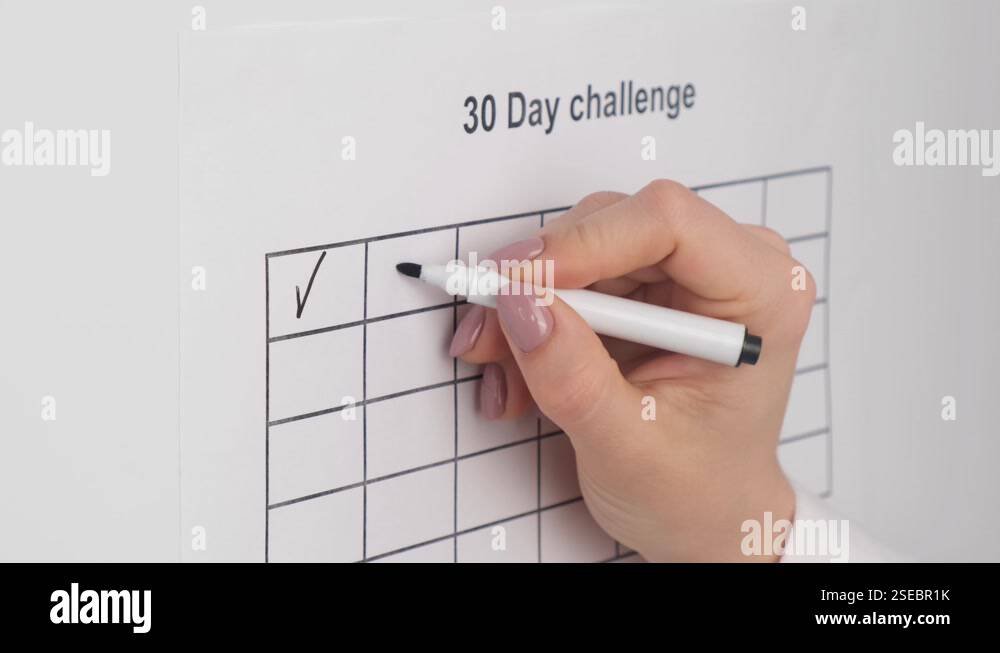 Cropped view of woman writing check marks in boxes of 30 days challenge ...