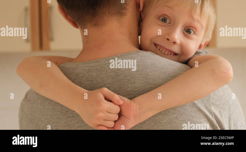 Surprised boy hugs his father. Son happily hugs his father by the ...