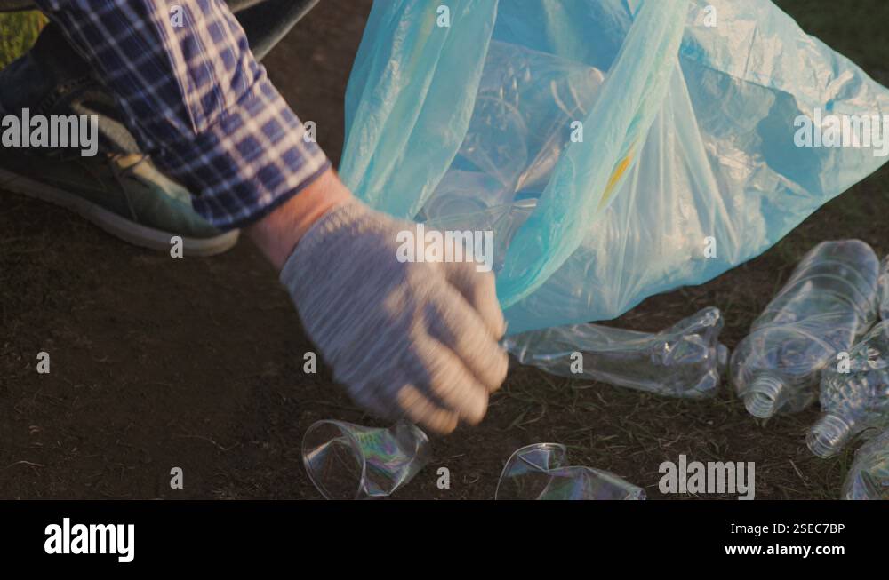 Male hand collects garbage in a garbage bag close-up, rid the planet of ...