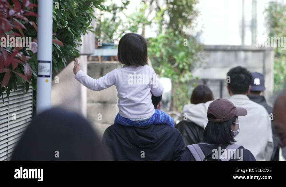 Back View Of A Little Girl Riding On Her Father's Shoulder During ...