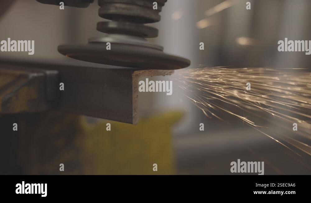 This is a close up of a man in fabrication shop grinding angle iron ...