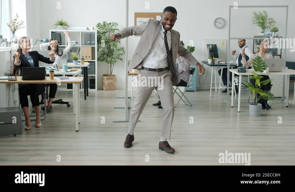 Portrait of enthusiastic African American employee dancing in workplace ...