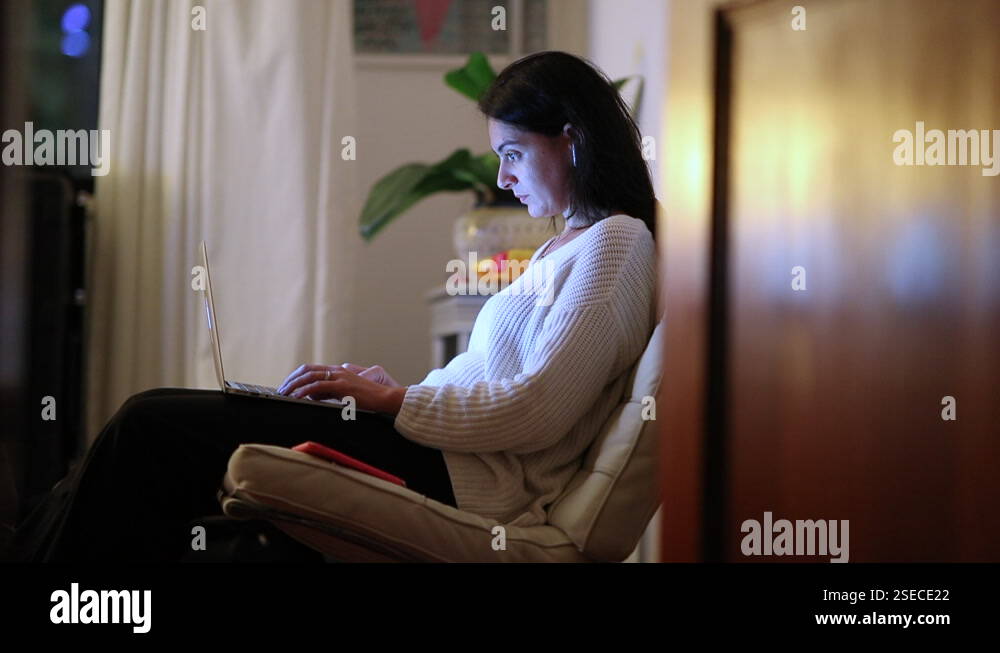 Woman working late at night in front of laptop computer sitting on ...