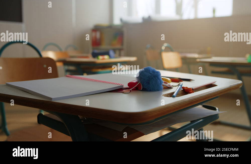 Notebook and pencils lying on desk in classroom. Table with school ...