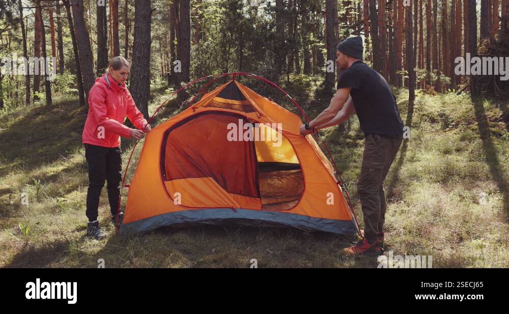 young couple set up a tent together in forest. outdoor adventure ...